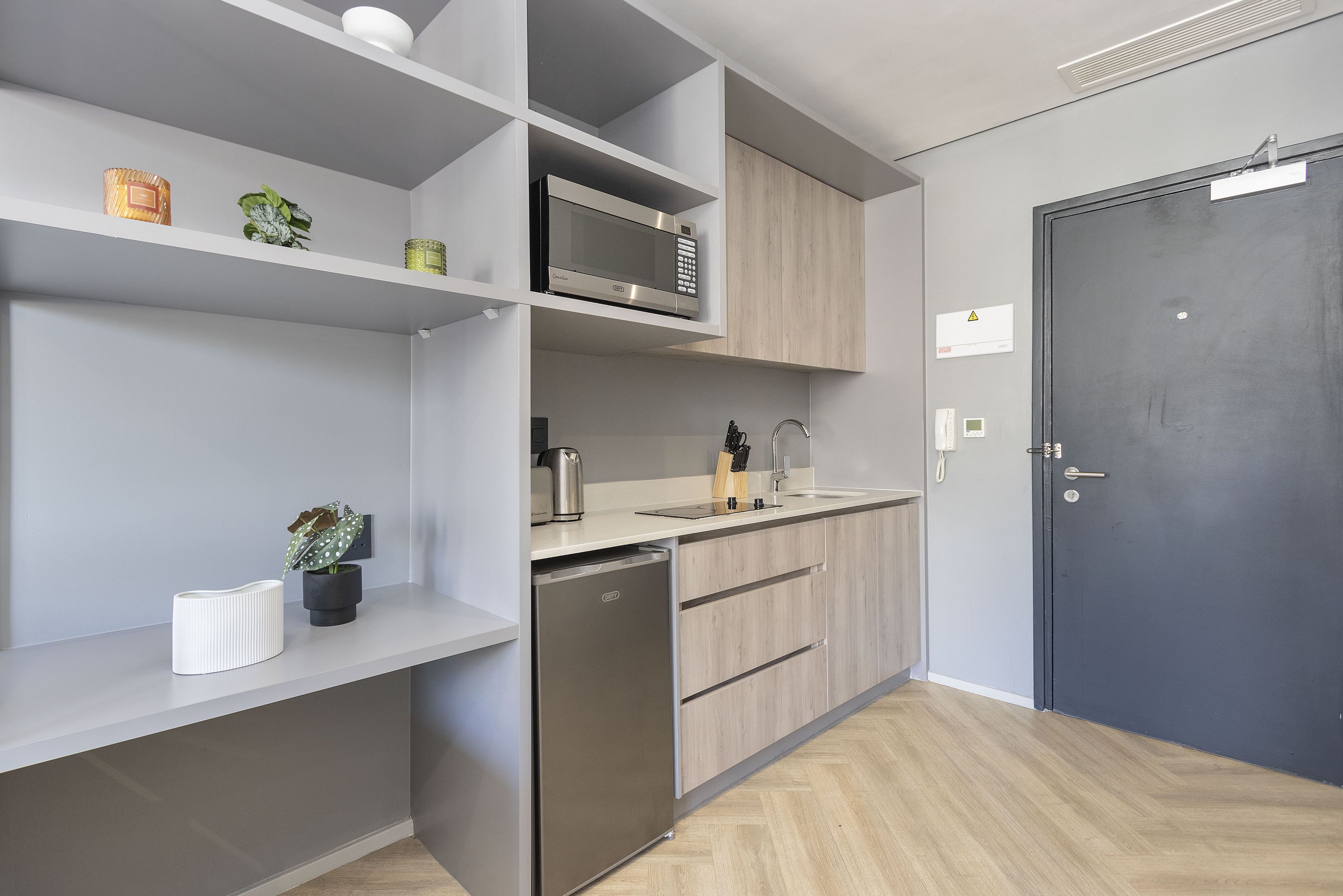 Cozinha moderna com eletrodomésticos embutidos, armários de madeira e porta escura.
