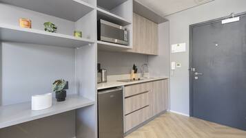Cozinha moderna com eletrodomésticos embutidos, armários de madeira e porta escura.