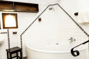Um banheiro com uma banheira branca, um banquinho de madeira, um porta-toalhas e um chuveiro com padrão de azulejos preto e branco.
