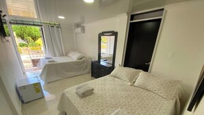 Quarto de hotel com duas camas, uma mesa pequena, um espelho e uma porta.