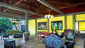 Um espaço amplo e arejado, com teto alto, um banco, uma mesa e cadeiras.
