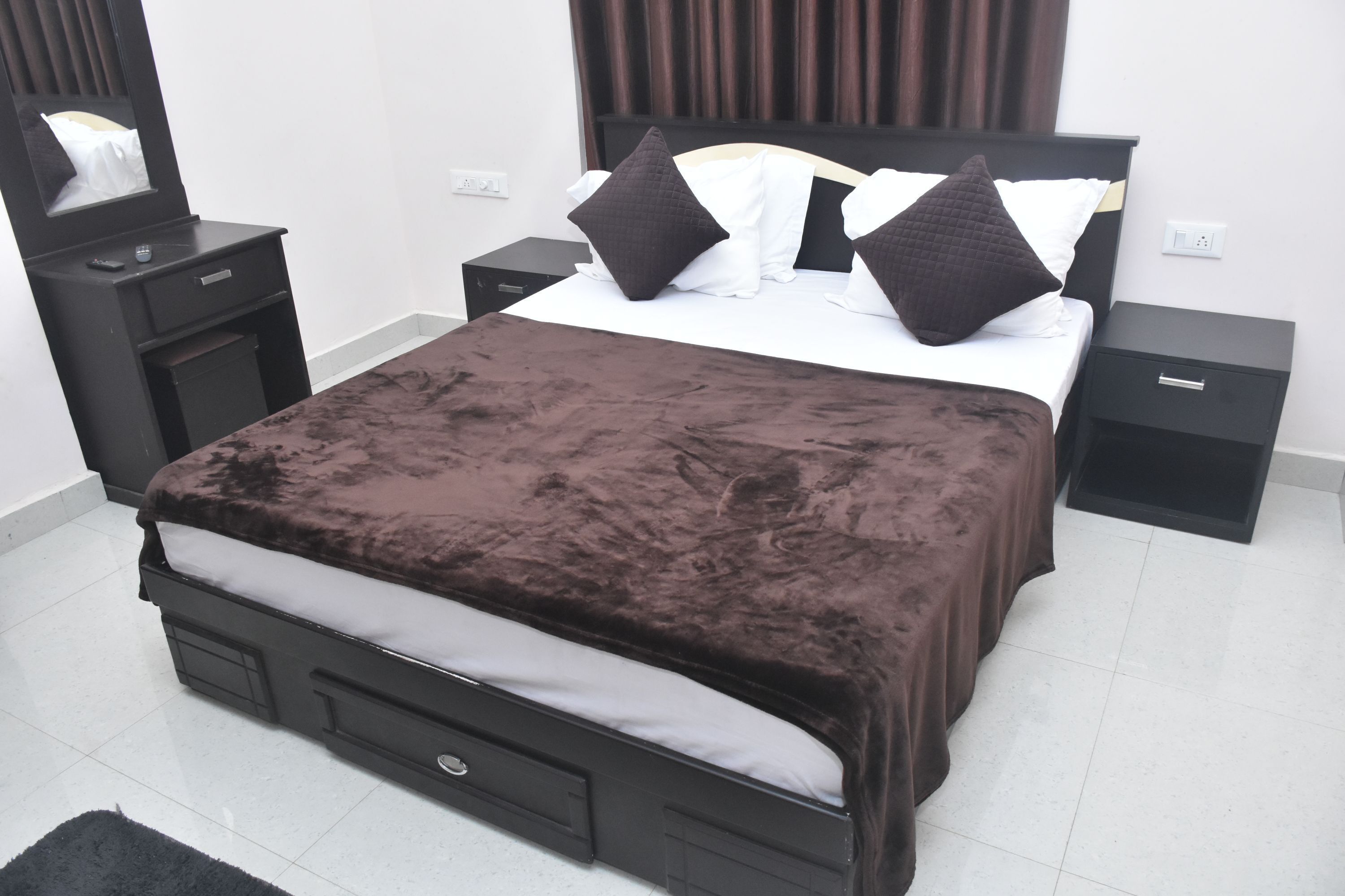 Quarto com cama grande, mesa de cabeceira, espelho e cômoda.