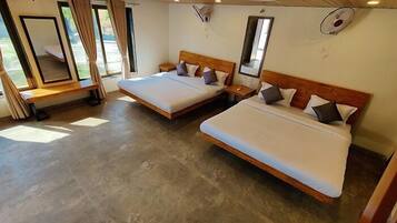 Quarto de hotel com duas camas, um banquinho e uma janela grande.