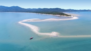 Uma extensa massa de água calma, com uma praia arenosa e um barco.