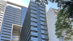 Um edifício moderno de grande porte com um design angular distinto, apresentando várias varandas e fachada de vidro.