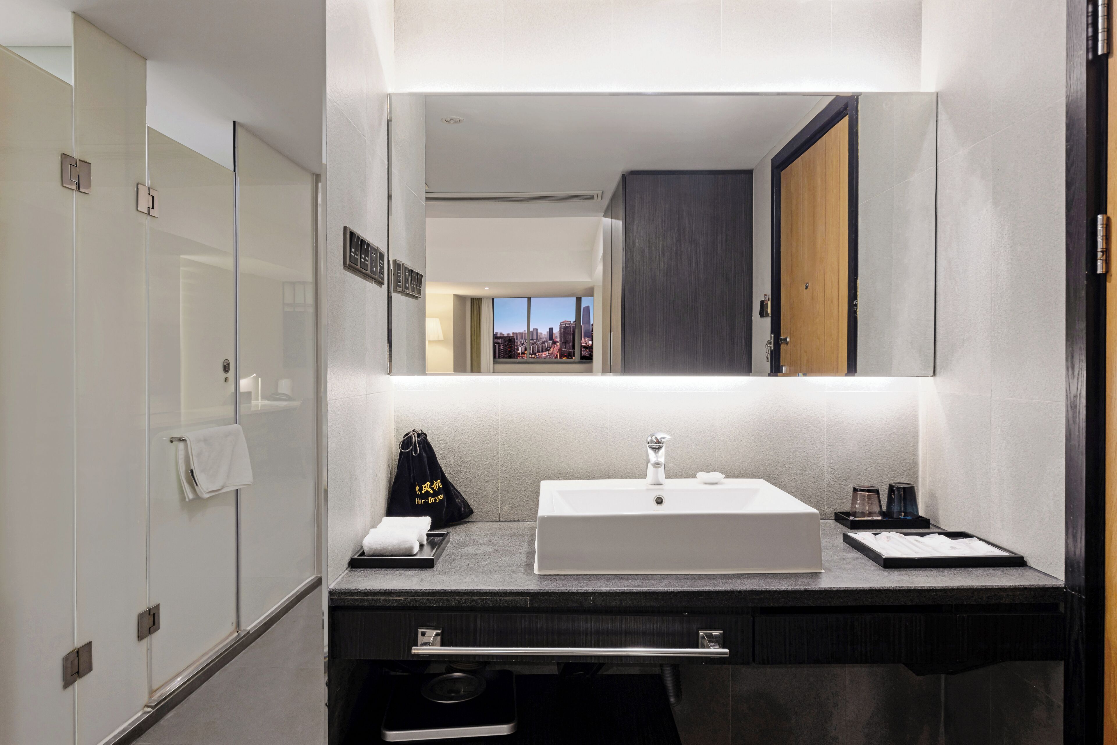 Uma casa de banho moderna com um espelho grande, uma sanita branca e um porta-toalhas.