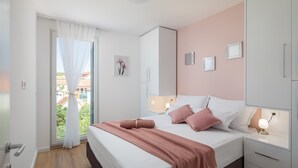 Quarto com cama, mesas de cabeceira, guarda-roupa e janela com cortinas.