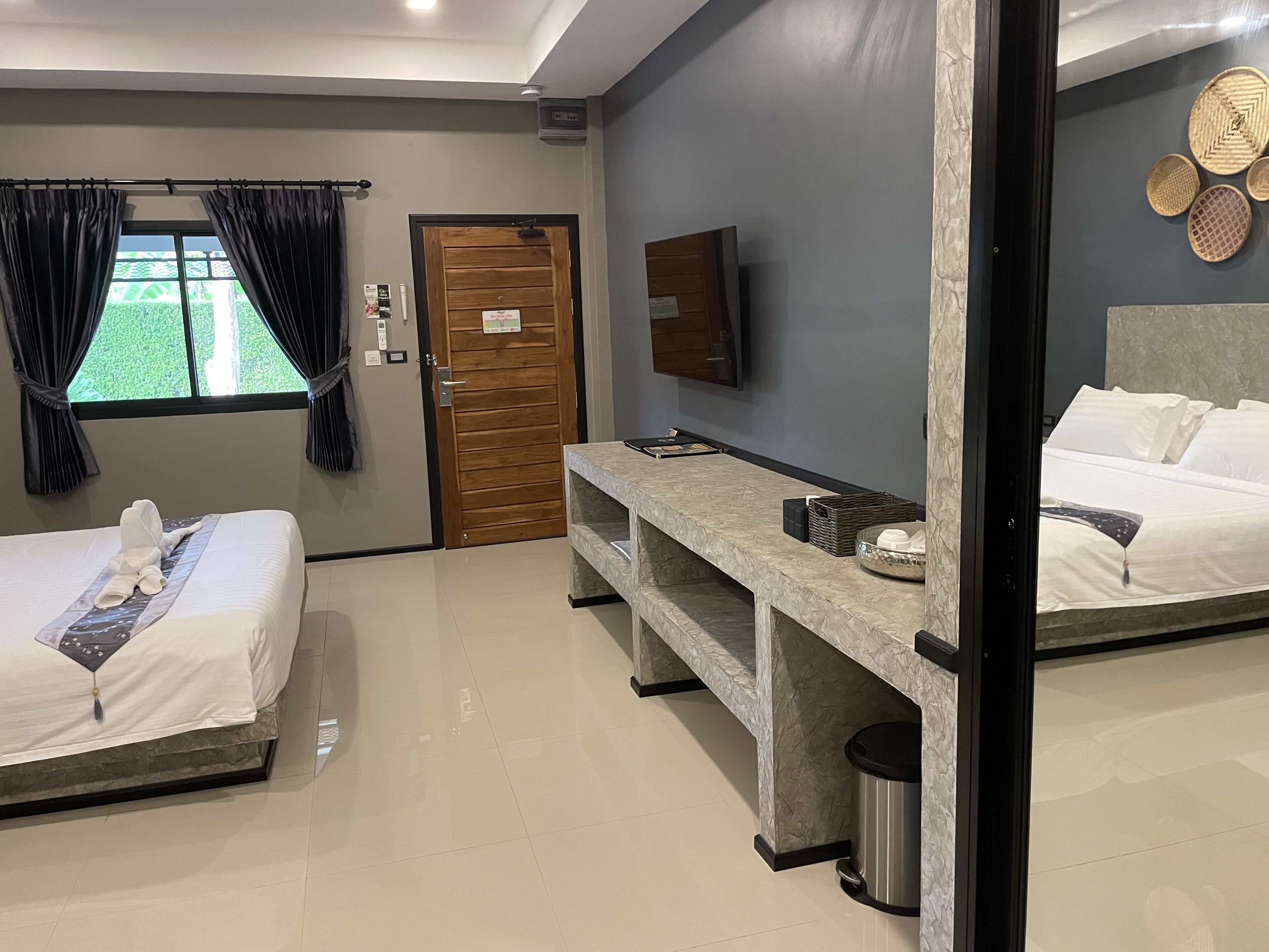 Quarto de hotel com duas camas, uma escrivaninha, um espelho e uma televisão.