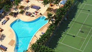 Uma piscina com design exclusivo, rodeada por espreguiçadeiras e palmeiras.