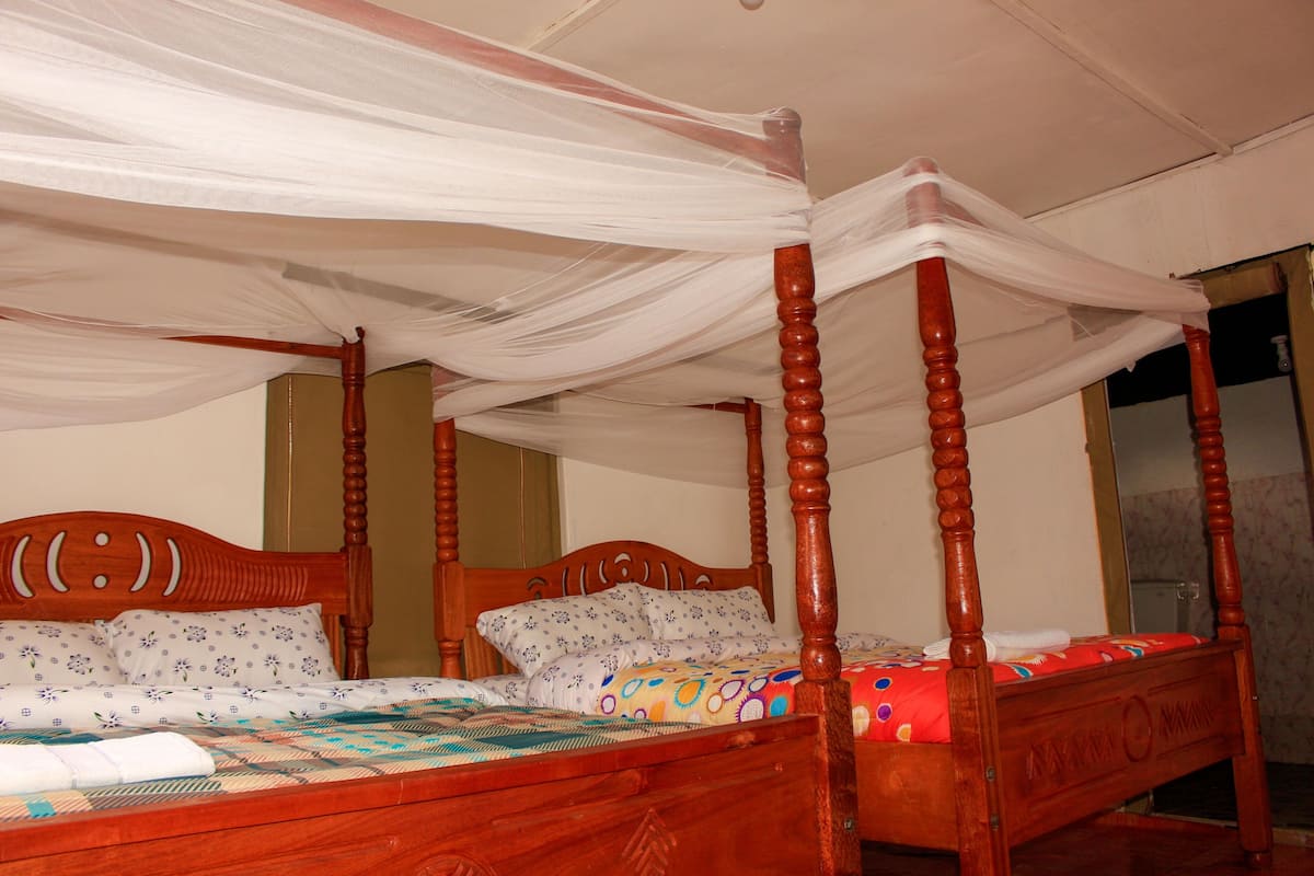 Uma cama com dossel, cabeceira de madeira e colcha estampada com motivos florais.