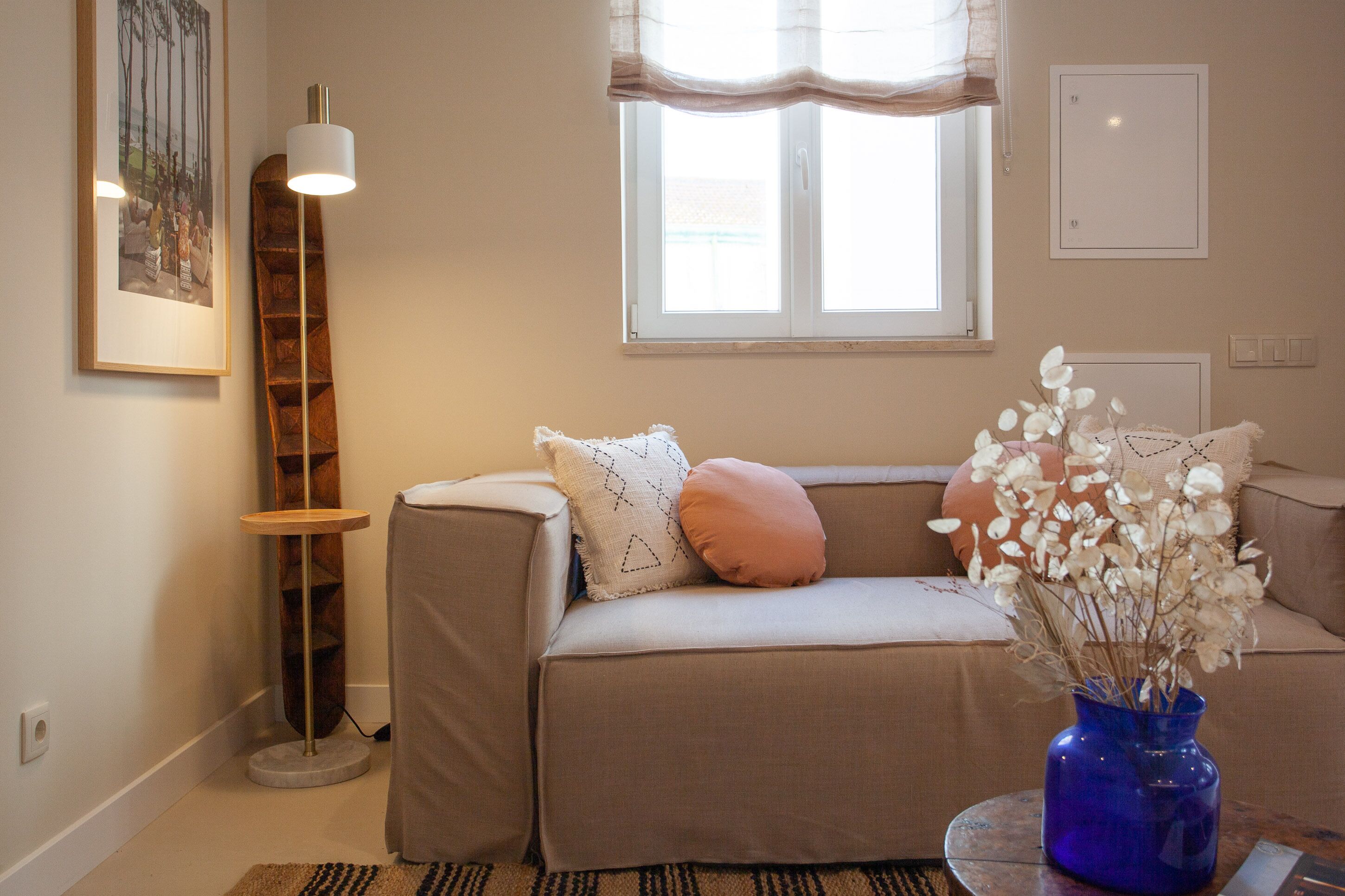 Uma sala de estar aconchegante com um sofá, uma mesa lateral com um vaso e um abajur.
