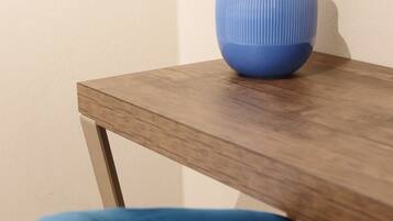 Uma cadeira azul e um vaso azul sobre uma mesa de madeira em frente a uma parede.