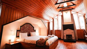 Um quarto aconchegante com teto de madeira, lareira e cama com cabeceira estampada.