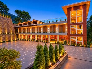 Um hotel moderno com vários andares, área de estar ao ar livre e fachada bem iluminada.