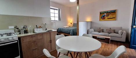 Um espaço compacto com cozinha compacta, mesa de jantar e sofá.