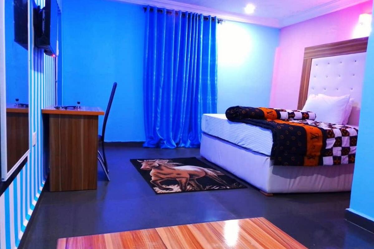 Um quarto com uma cama, uma escrivaninha e uma cortina azul.