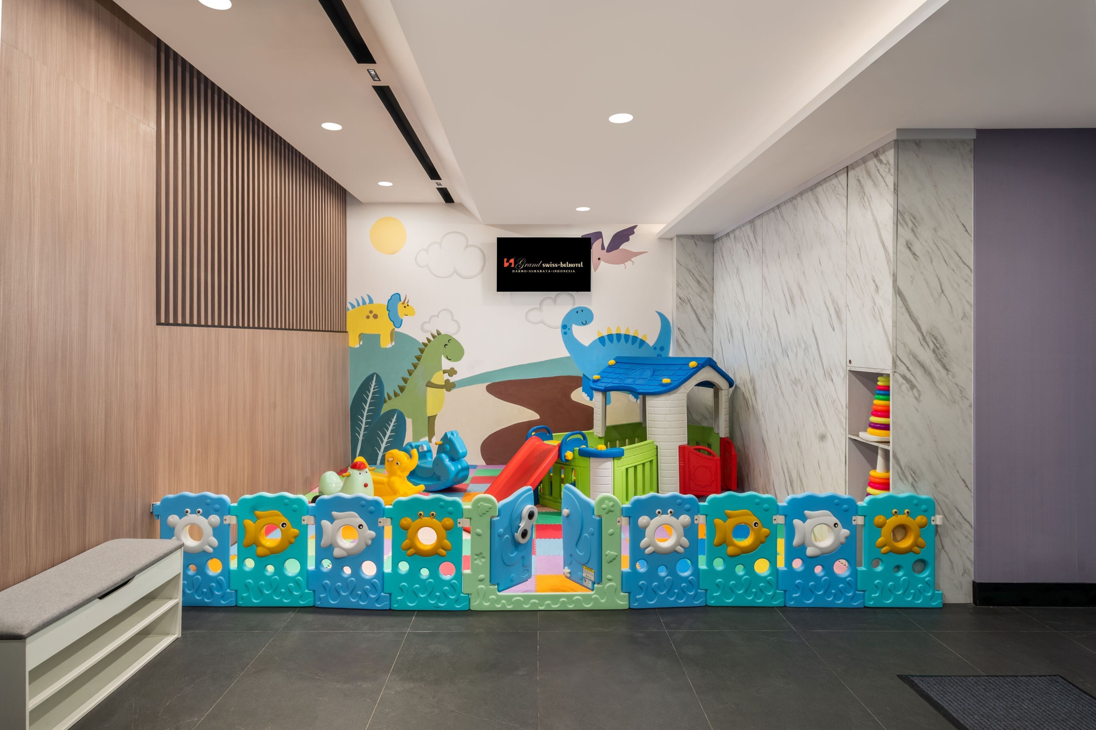 Espaço infantil com escorrega, estruturas de escalada e um mural.