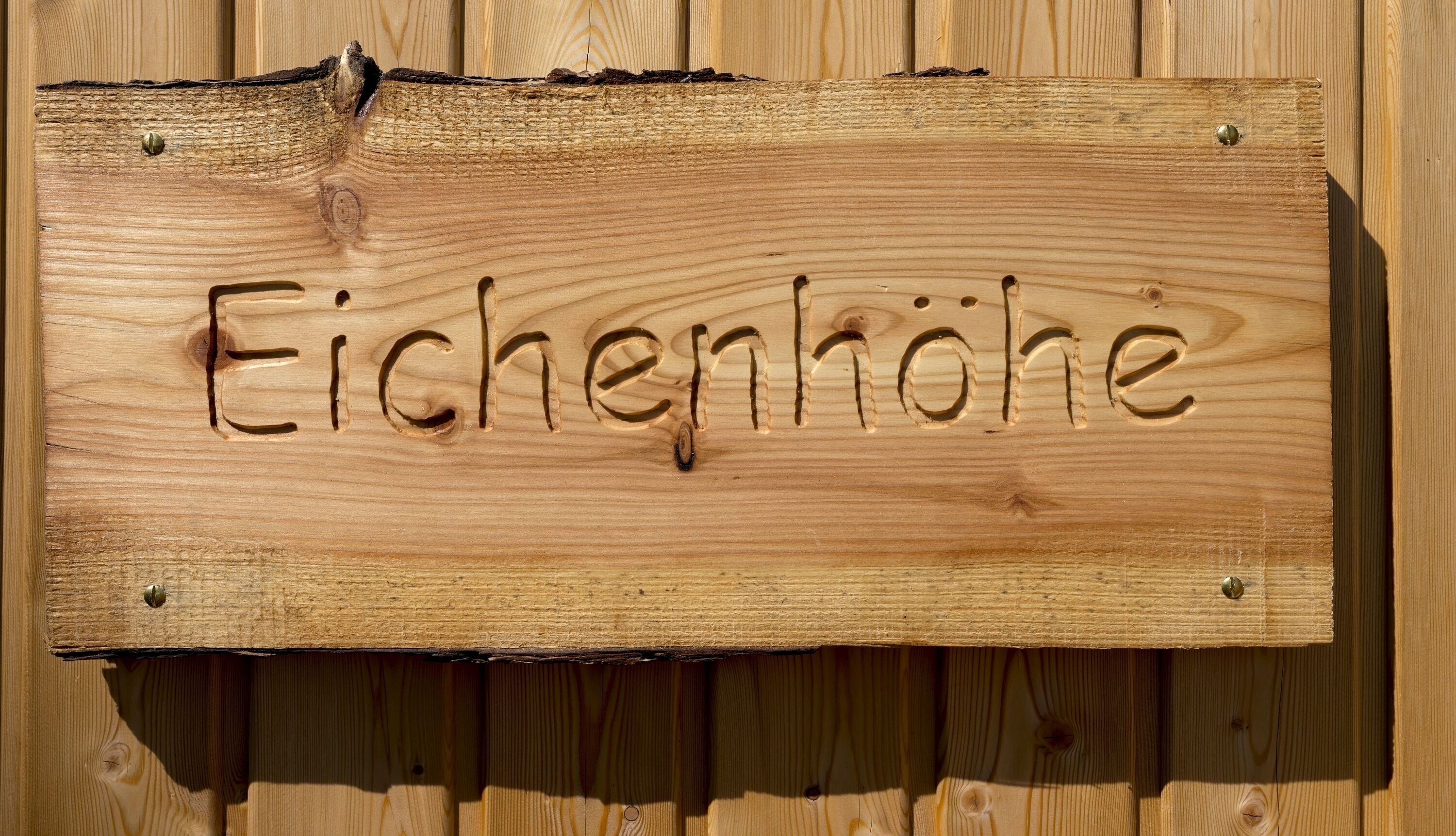 Uma placa de madeira com o texto 'Eichenhöhe' entalhado.