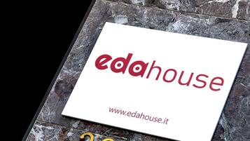 Um sinal com o texto 'edahouse' e o endereço do site 'www.edahouse.it' sobre uma superfície de mármore.