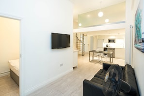 Apartamento, várias camas | Área de estar | TV de tela plana