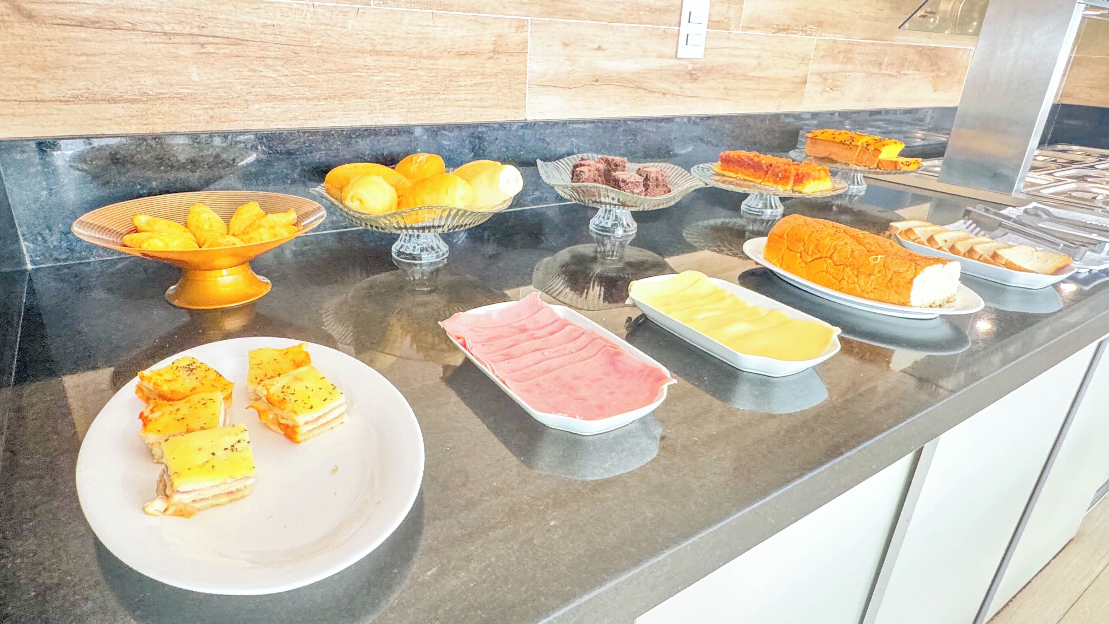 Buffet com diversos pratos, incluindo doces, carnes e queijos.