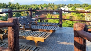 Um deck de madeira com bancos, com vista para uma paisagem deslumbrante com montanhas e vegetação.