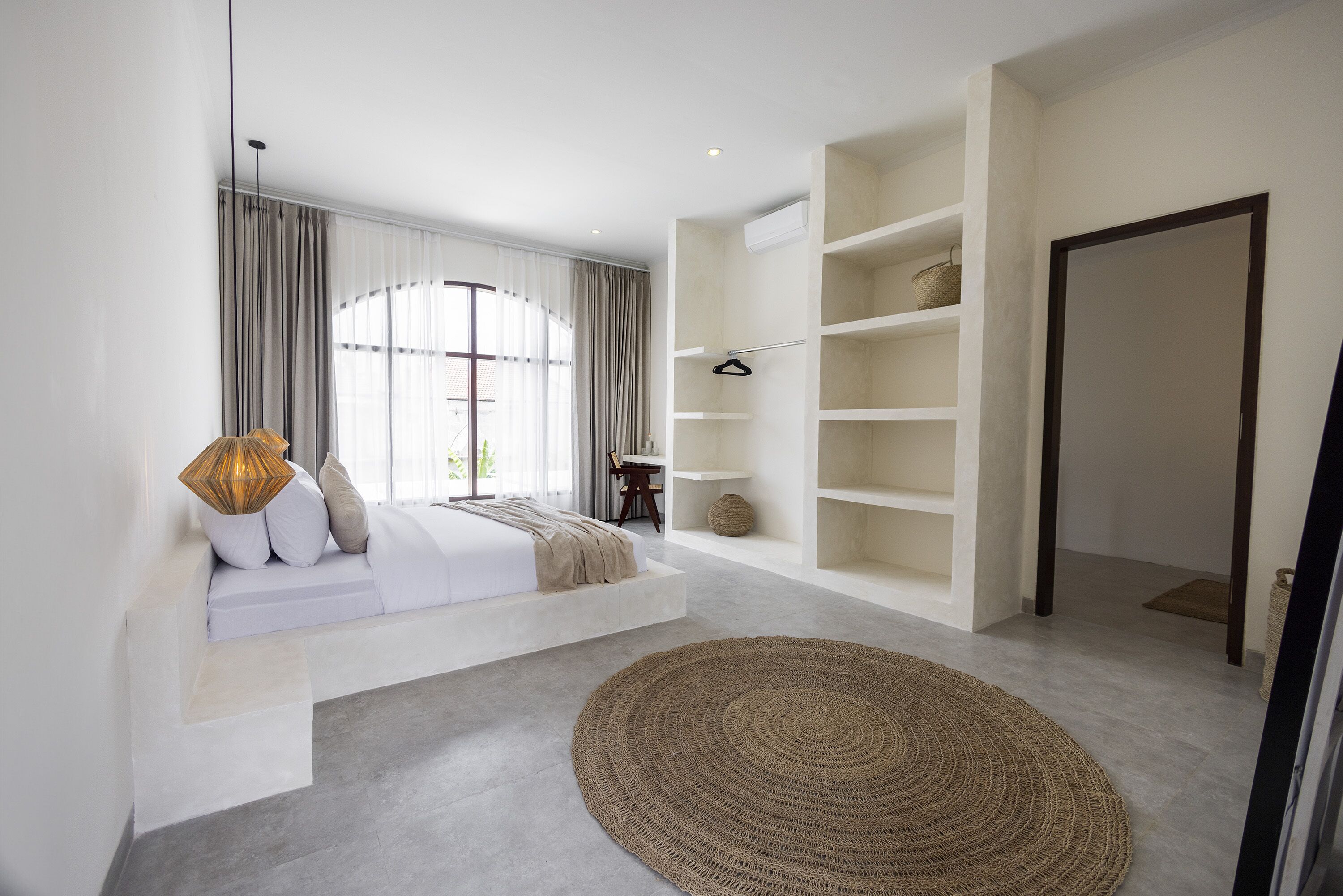 Quarto moderno com um banco embutido, um tapete grande tecido e uma estante minimalista.