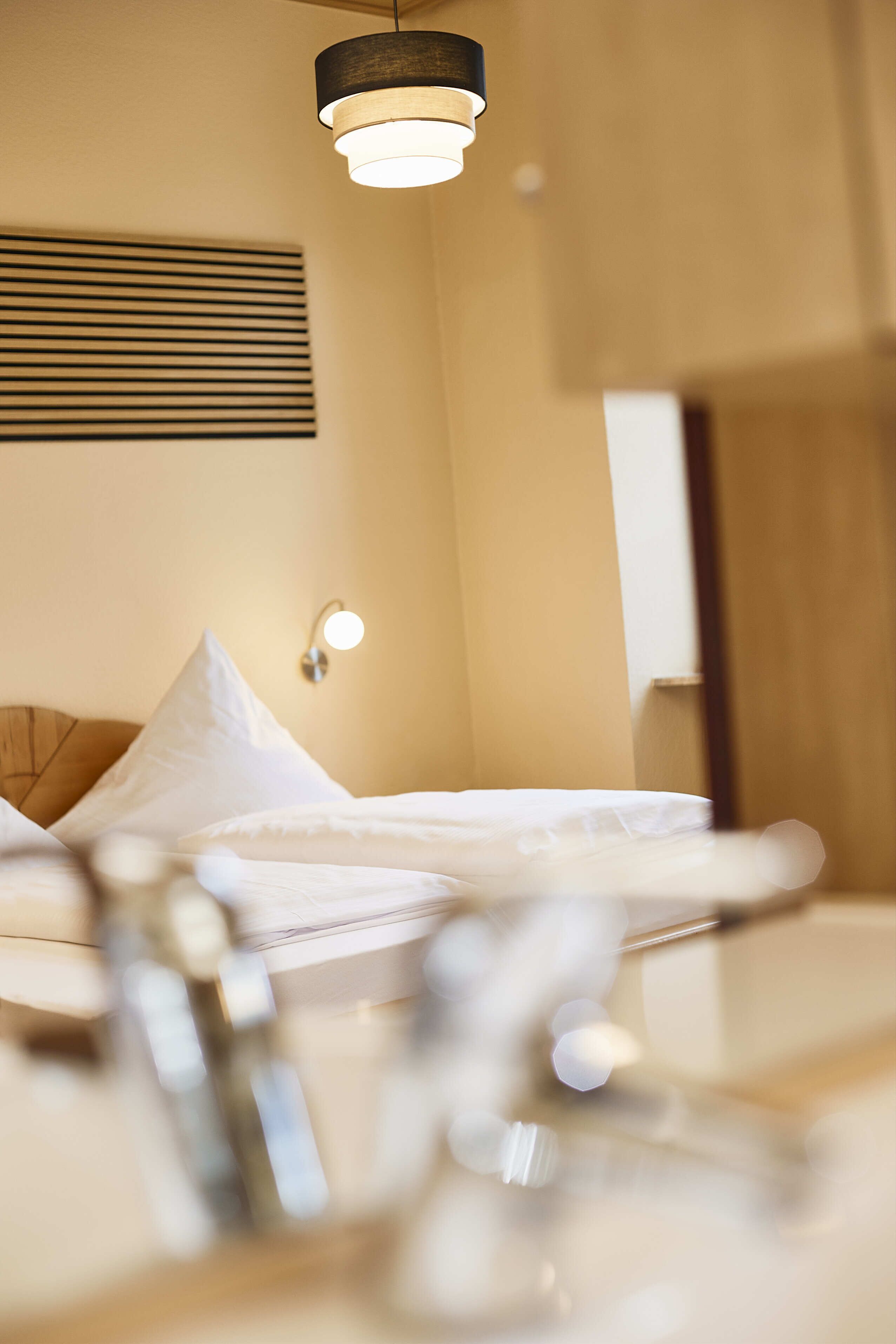 Quarto de hotel com cama, abajur e janela.