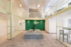 Um átrio amplo com parede verde, um letreiro de neon e uma lareira de tijolos.