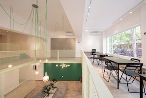 Um interior moderno com uma parede verde, luminárias pendentes e vista para o exterior.