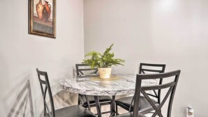 Uma área de refeições com uma mesa redonda, quatro cadeiras pretas e um vaso de planta.