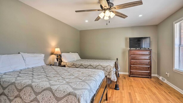 Quarto com duas camas, um ventilador de teto, uma TV e uma cômoda.