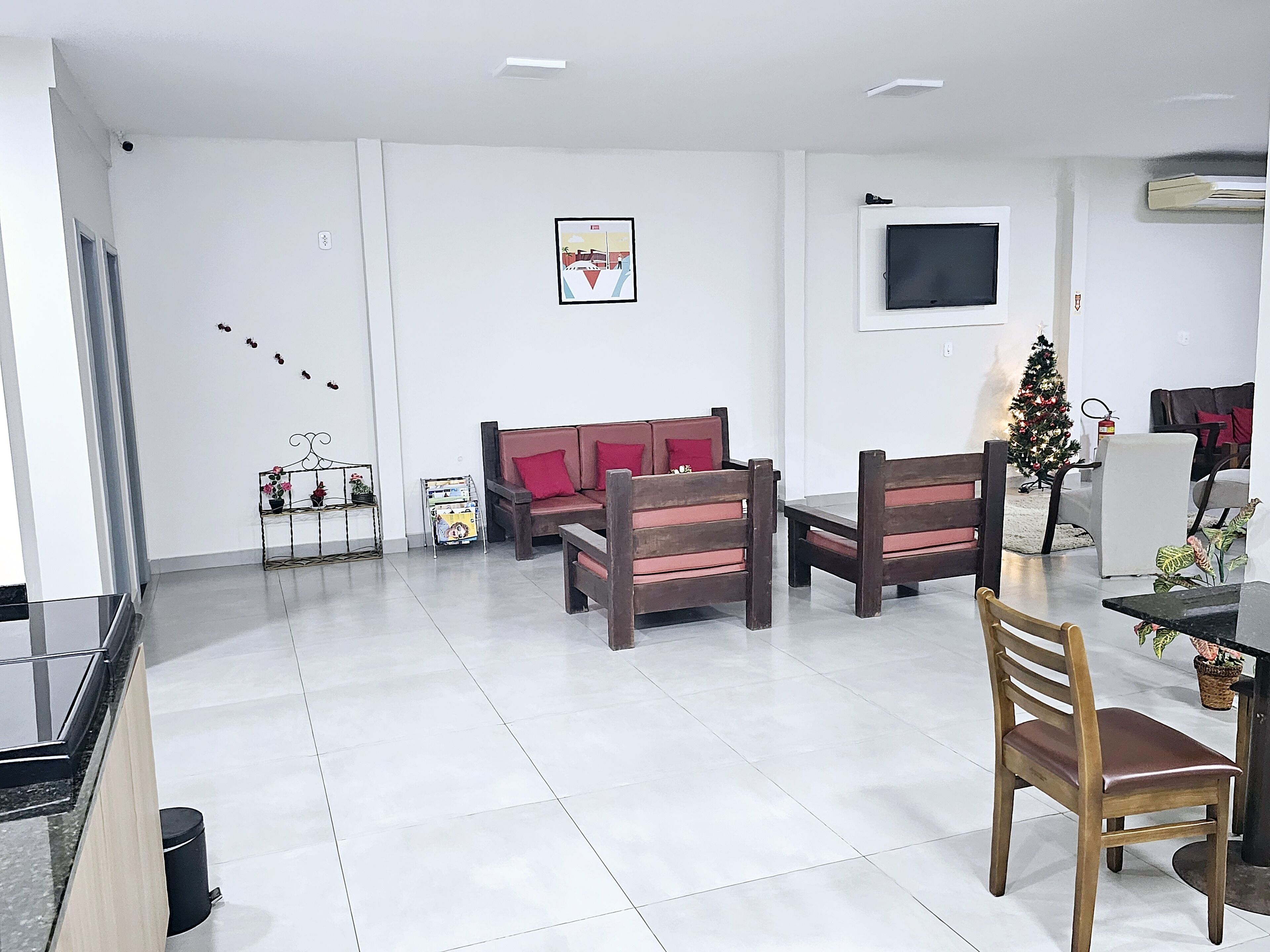Uma sala de estar moderna com um sofá, duas cadeiras de madeira, uma mesinha e uma televisão na parede.