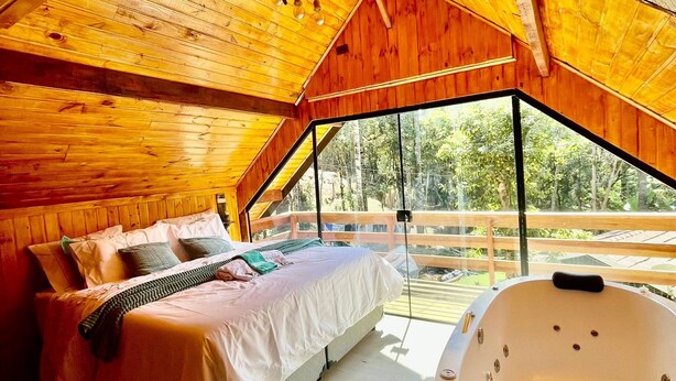 Quarto com cama grande, banheira e vista para o exterior.