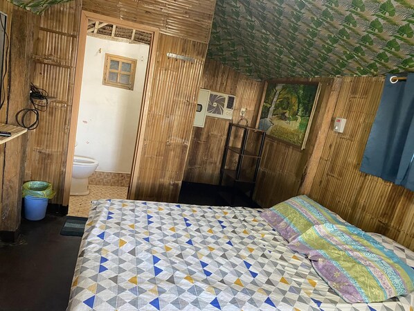 Quarto com uma cama, parede de madeira, janela, porta e banheiro.