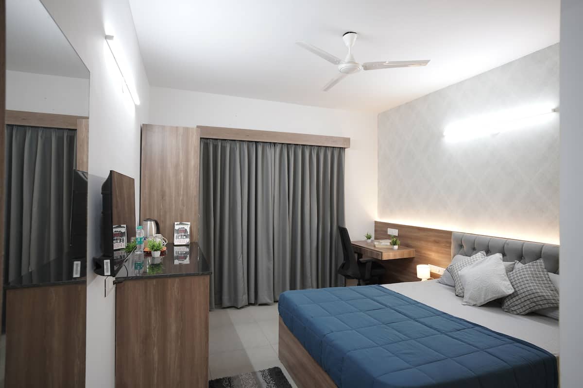 Quarto de hotel moderno com cama, escrivaninha e ventoinha no teto.