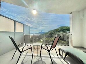 Varanda com mesa e cadeiras, oferecendo vista de uma paisagem montanhosa.
