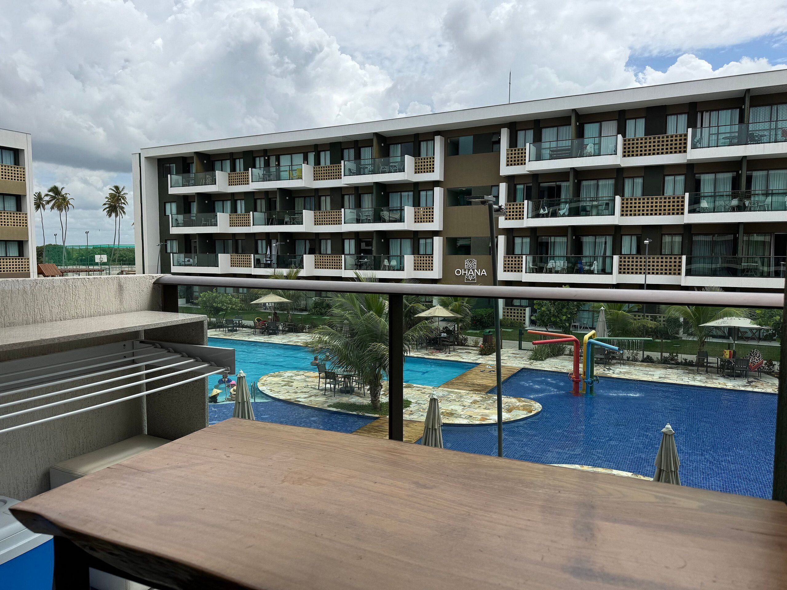 Um hotel com várias varandas, piscina e áreas de estar ao ar livre.
