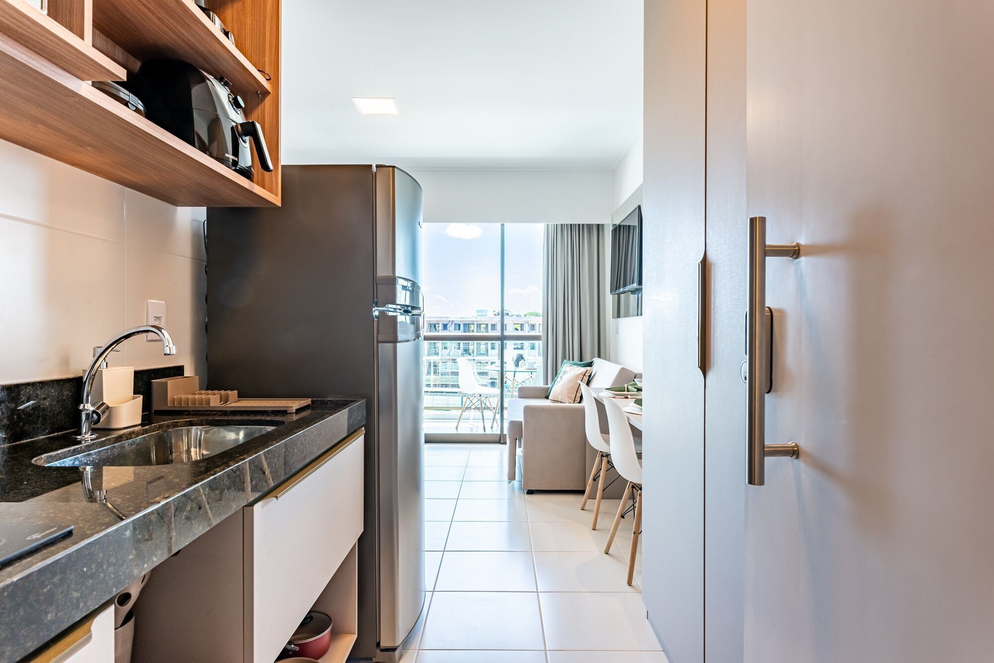Uma cozinha moderna com forno embutido, pia e janela com vista para a paisagem urbana.