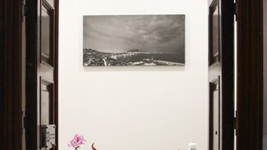 Uma receção com uma placa de "Bem-vindo", uma fotografia emoldurada na parede e uma pequena planta num vaso.