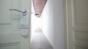 Corredor com uma placa na porta instruindo a arrumar o quarto.