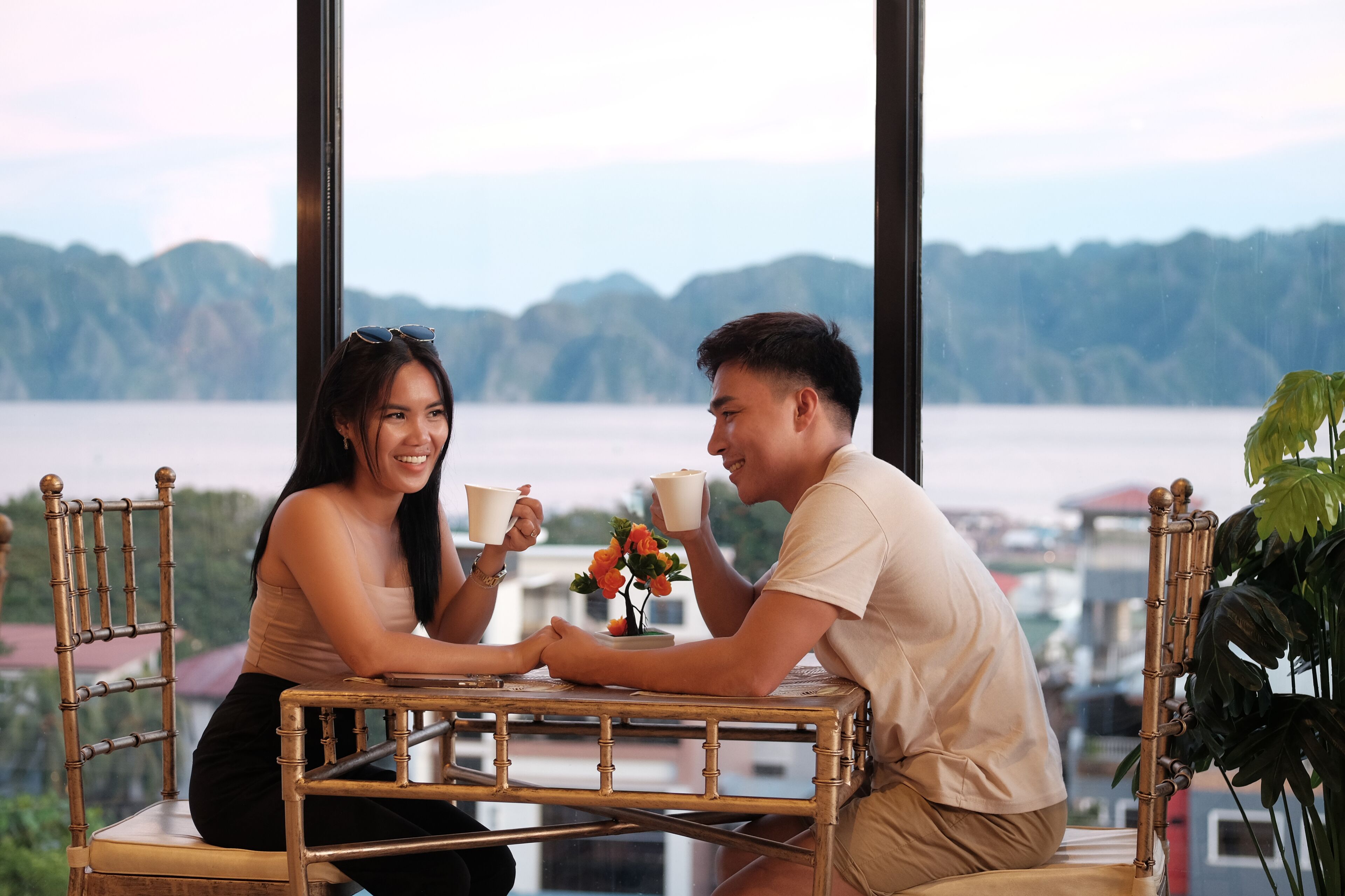 Um casal sentado à mesa com vista para a água e montanhas.