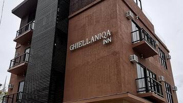 Um edifício de vários andares com a placa 'GHIELLANIA INN' na fachada.