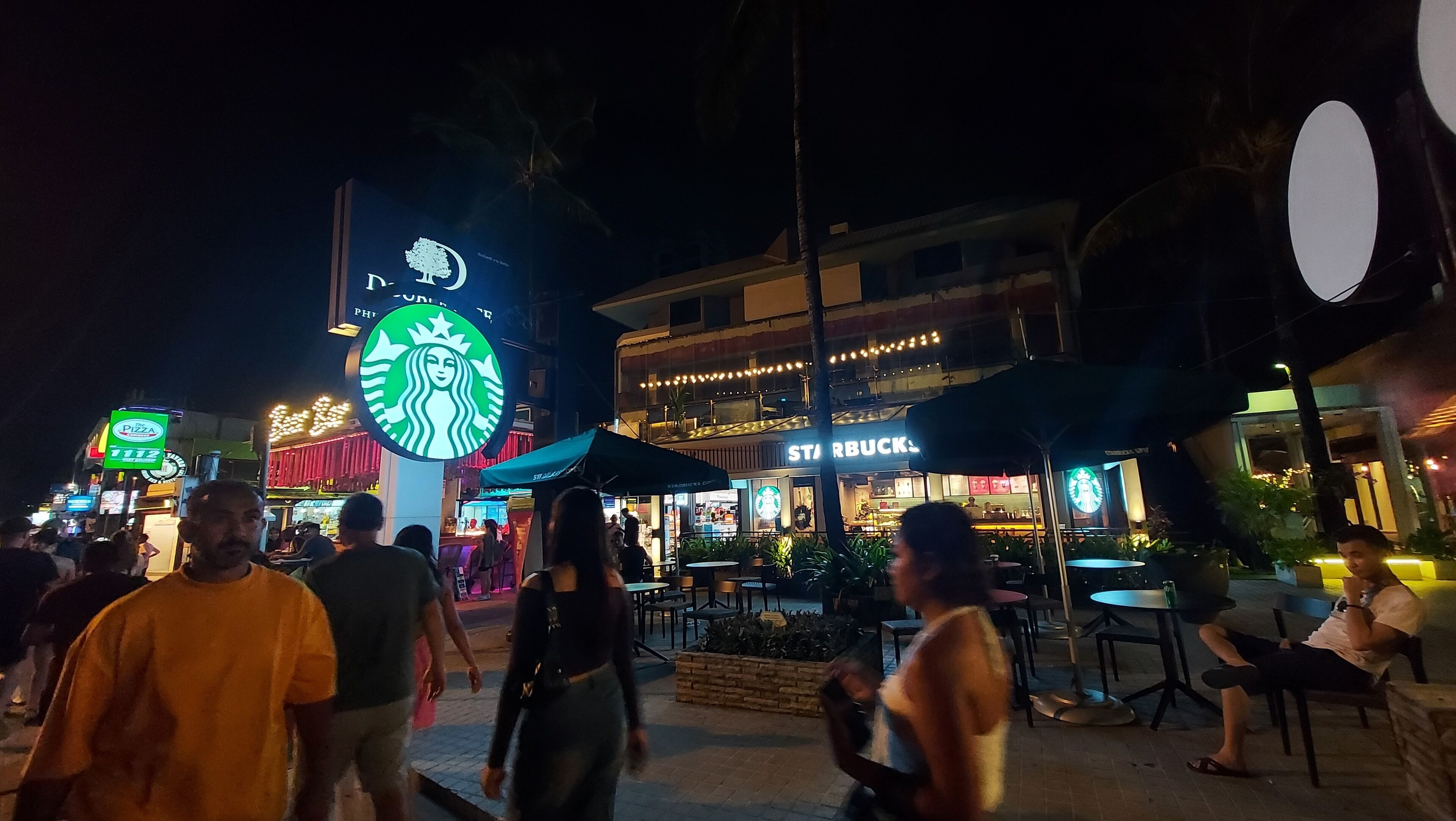 Uma rua movimentada com uma Starbucks e uma Pizza Hut.