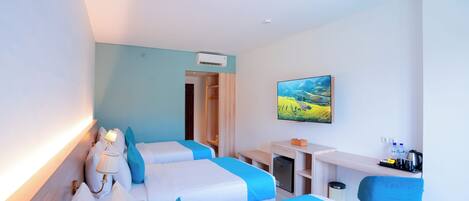 Quarto de hotel com duas camas, uma escrivaninha, uma cadeira, uma televisão e aparelho de ar condicionado.