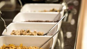 Buffet com diversos alimentos, incluindo cereais e ovos, em ambiente interno bem iluminado.