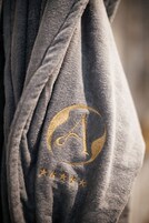Close-up de um roupão cinza com monograma dourado bordado e estrelas.