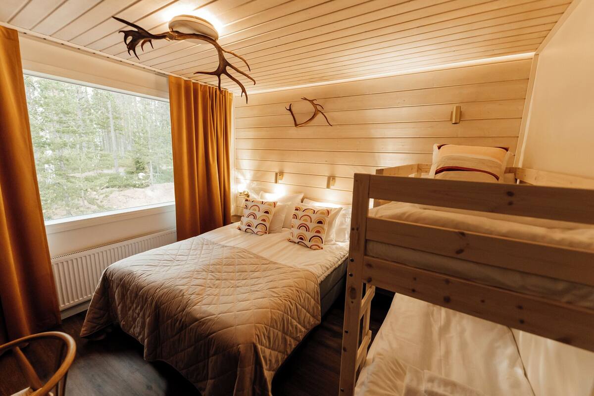 Um quarto aconchegante com uma cama, uma beliche e uma janela com cortinas.