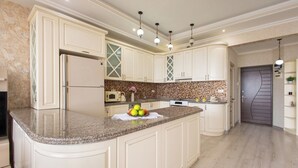 Cozinha com armários brancos, bancadas de granito, ilha central e backsplash com padrão de mosaico.