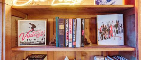 Uma estante de madeira com livros e um letreiro de neon que diz 'Ski Lodge'.